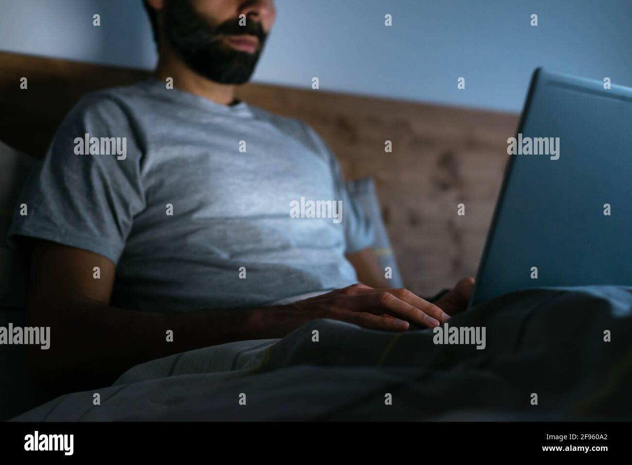 Crop man using a laptop on bed at night Stock Photo - Alamy