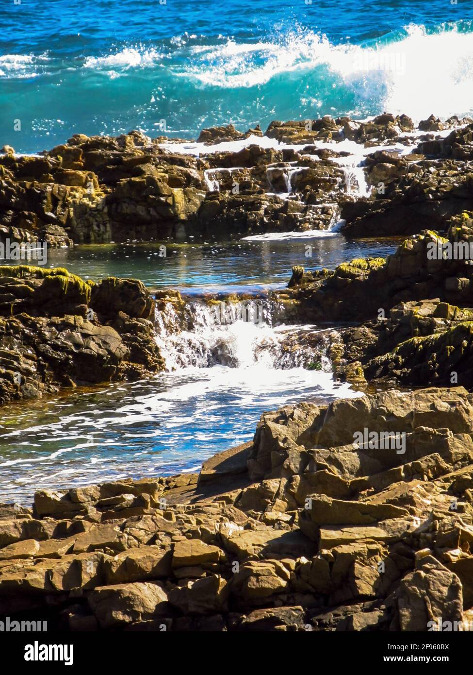 Water cascading between two different tidepools after a wave hit, at ...