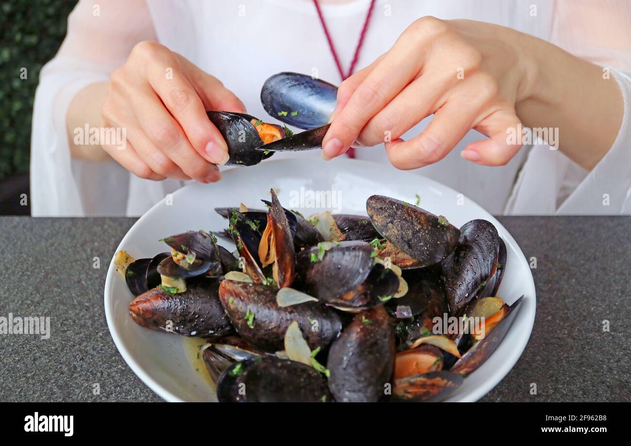 Woman Having her Steamed Mussels in White Wine by Using an Empty Mussel ...