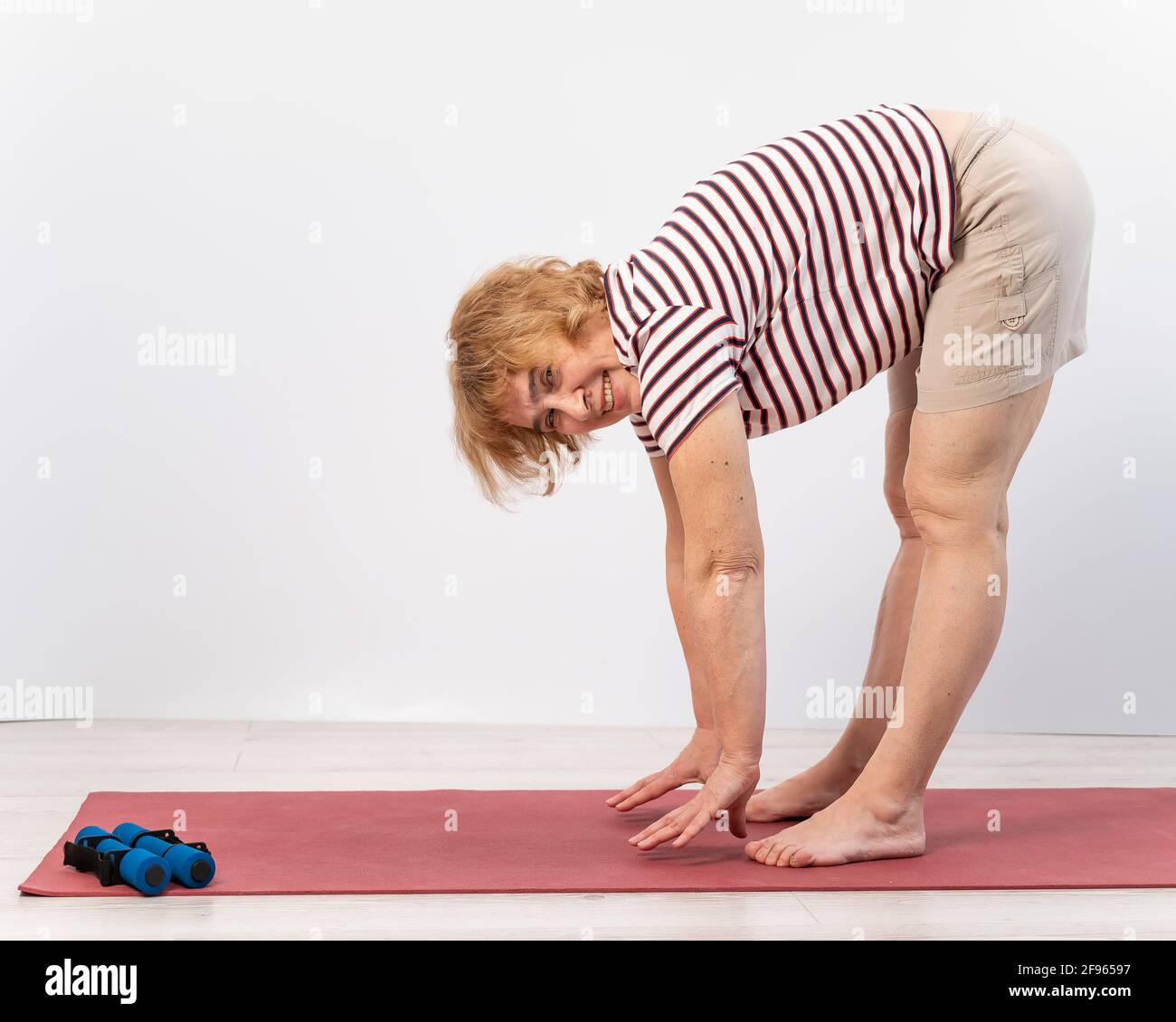 Elderly woman makes bends on a white background. Old lady doing health ...
