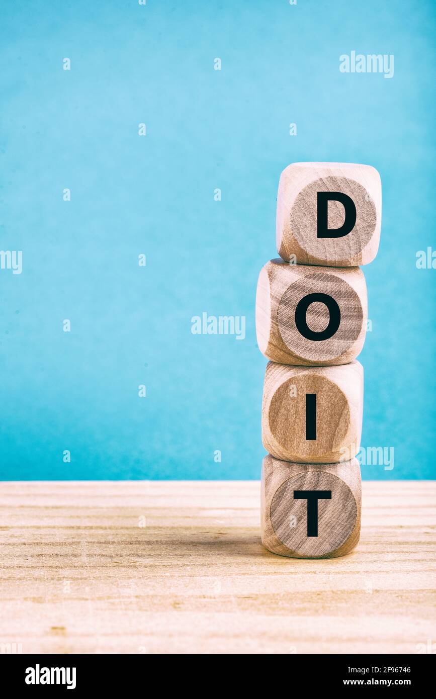 Phrase DO IT formed with wooden blocks in the blue background ...
