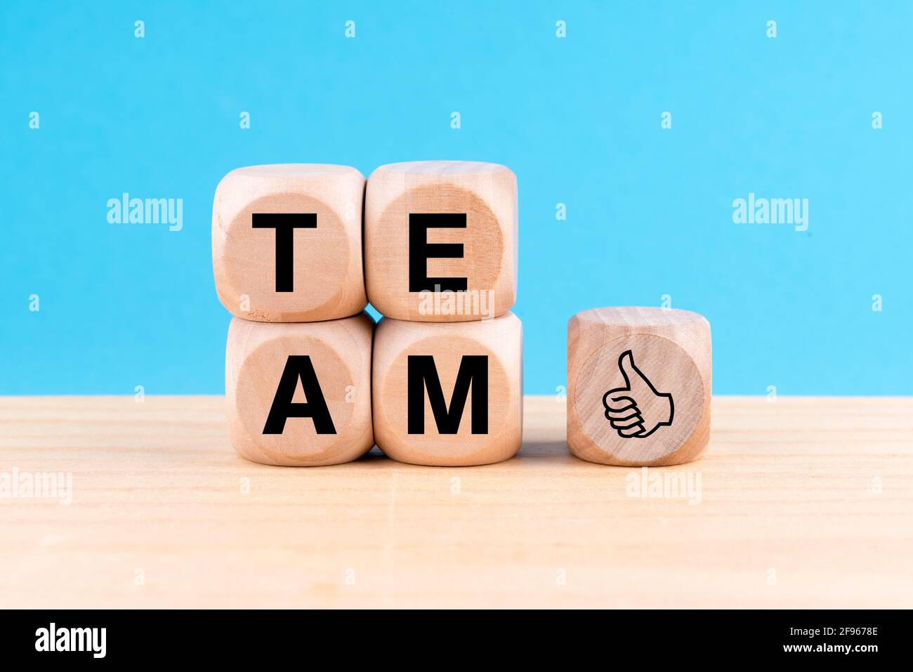 Word TEAM formed with wooden blocks and thumbs up icon in the blue ...