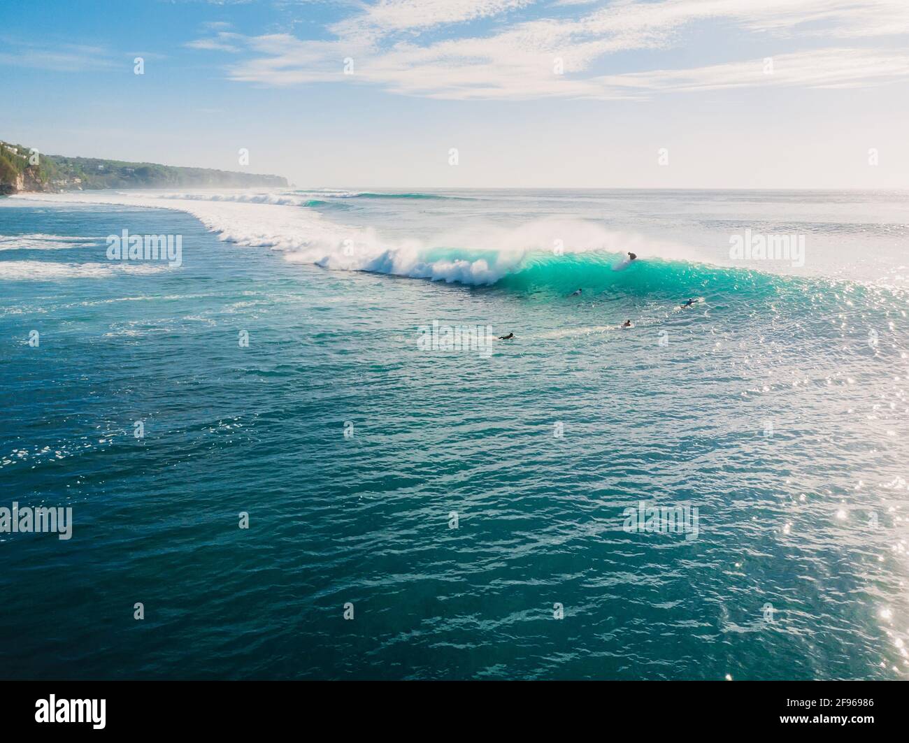 Blue wave with surfers in ocean, drone shot. Aerial view of barrel ...