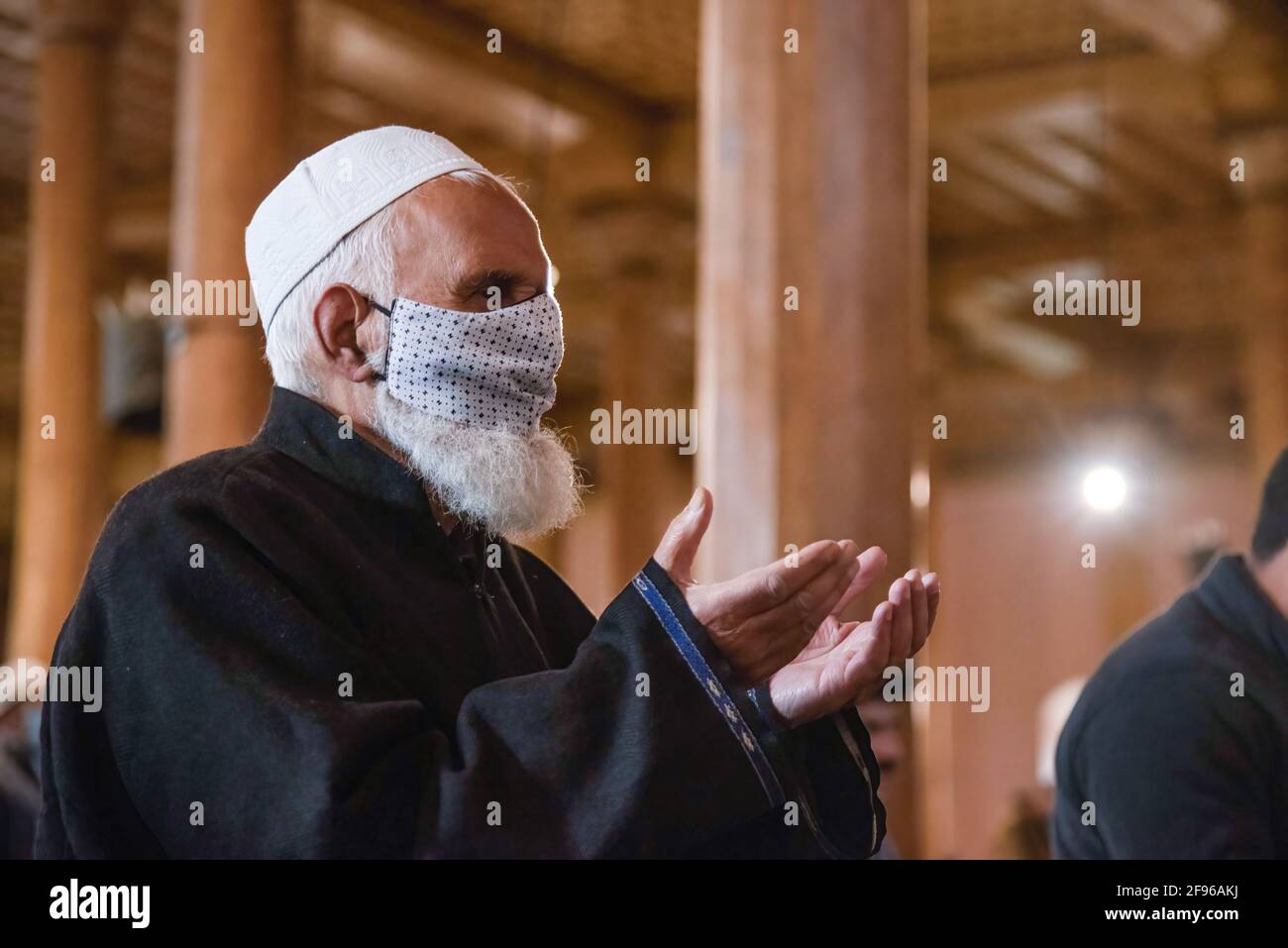 A Kashmiri Muslim wearing a face mask offers prayers on the first ...