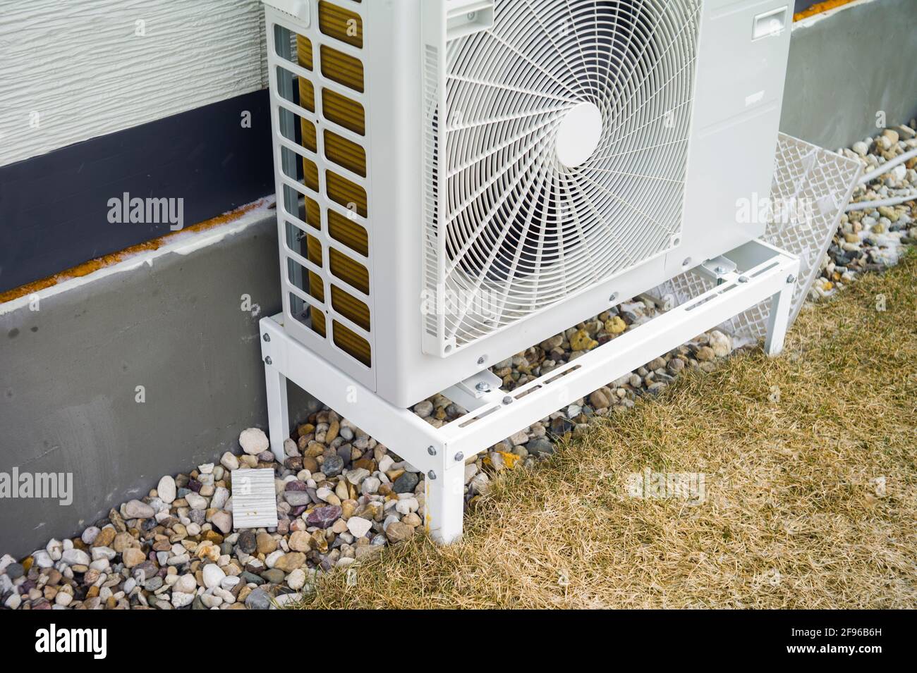 Air conditioner compressor mounted on the wall of a house, outdoor shot ...