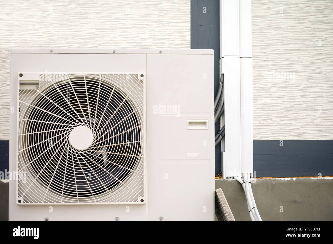 Air conditioner compressor mounted on the wall of a house, outdoor ...
