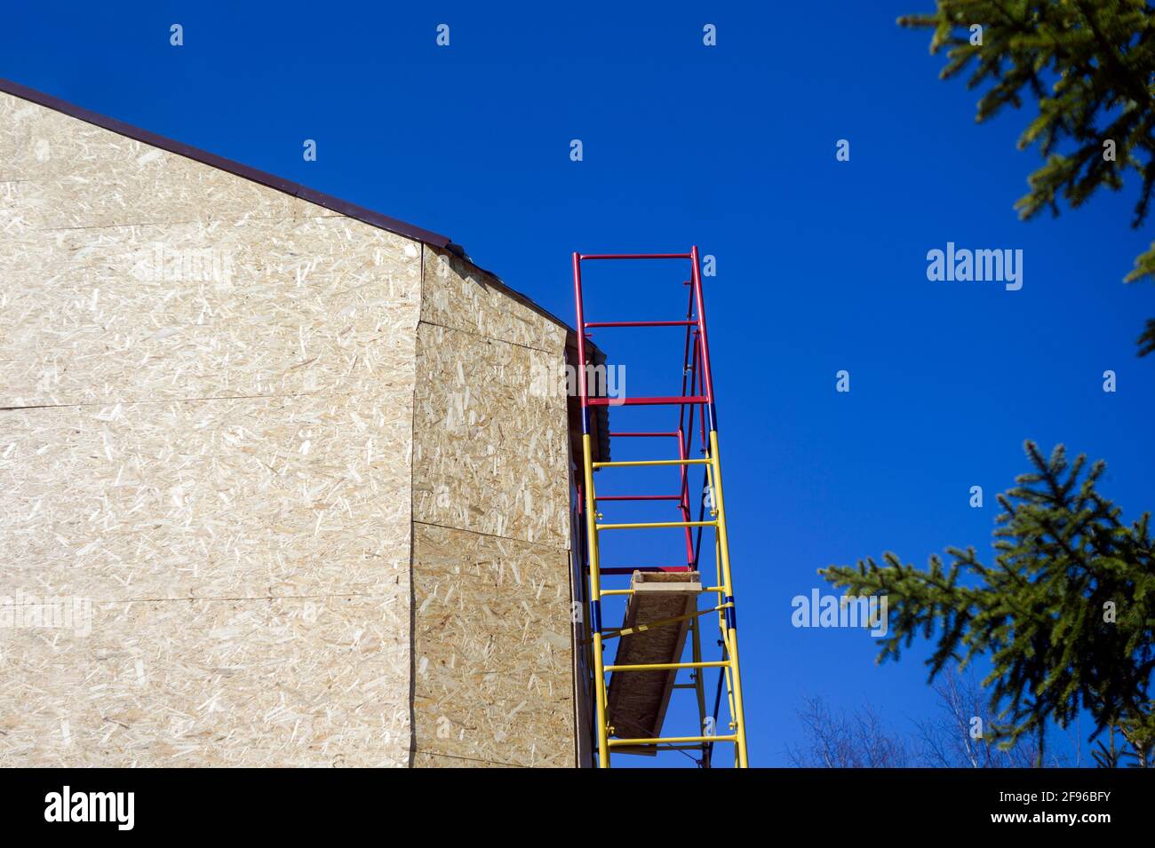Scaffolding and a building covered with chipboard against the blue sky ...