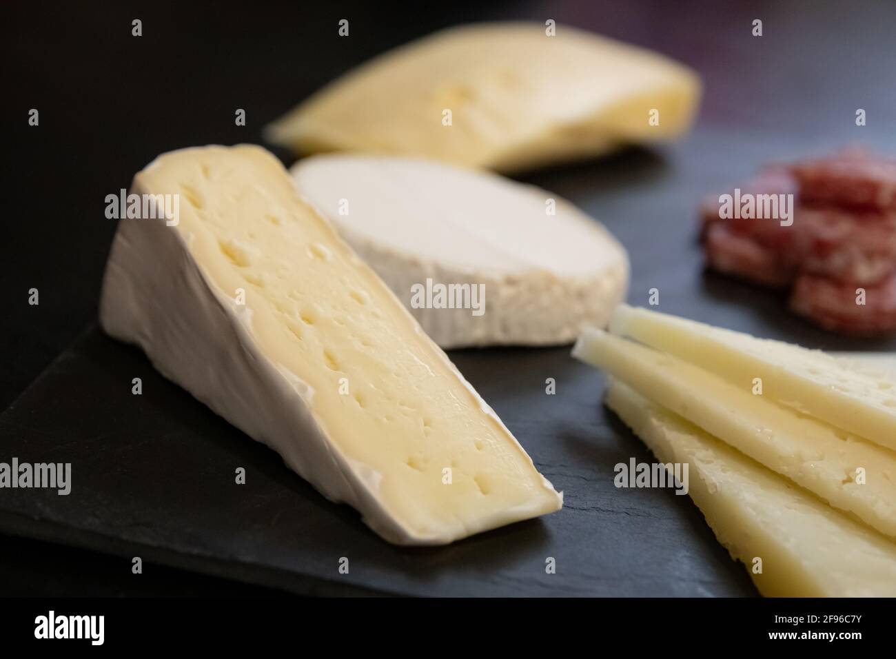 High angle shot of different kinds of cheese and salami on a black ...