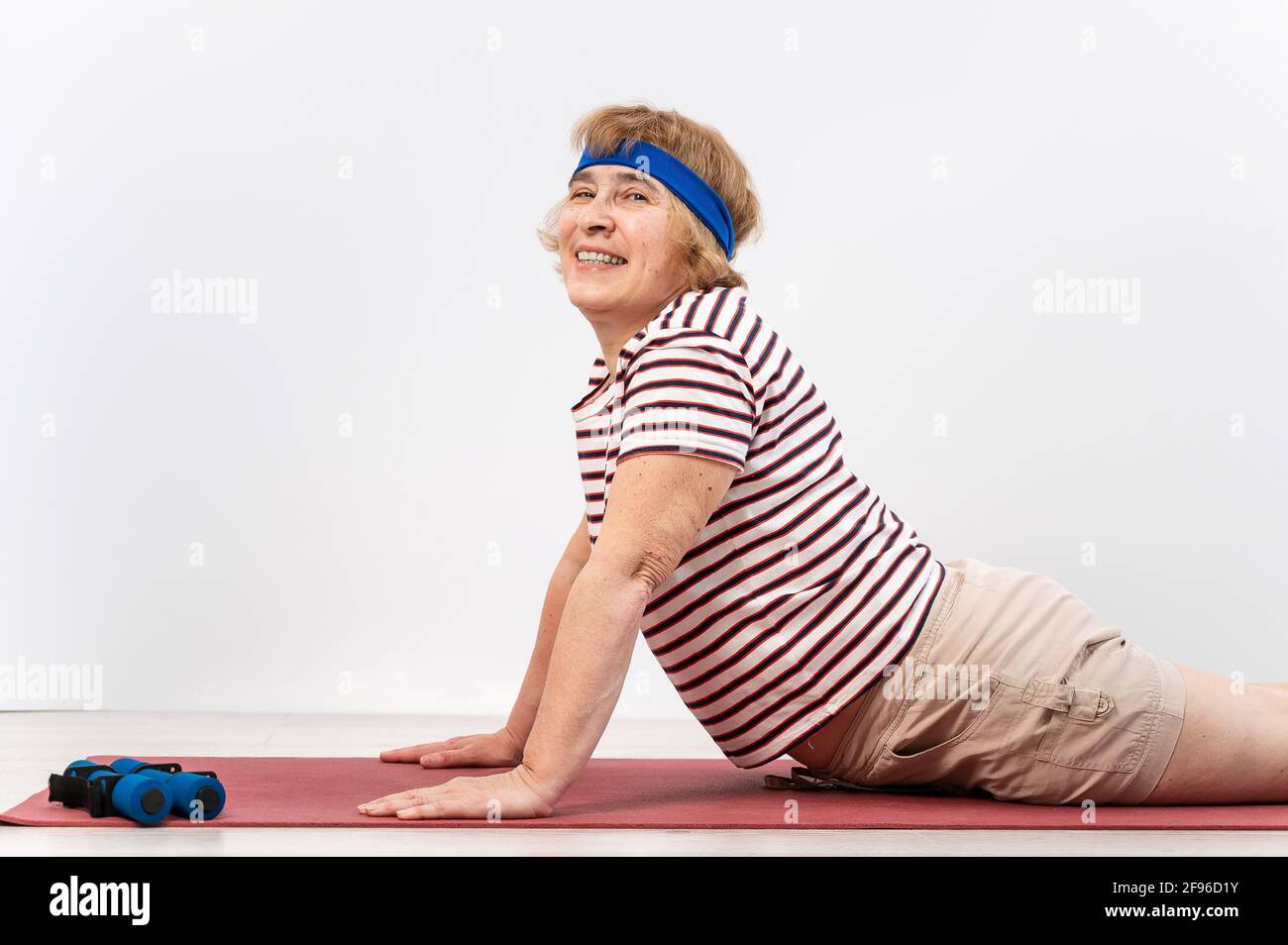 Elderly woman doing exercises in the studio on a white background. The ...