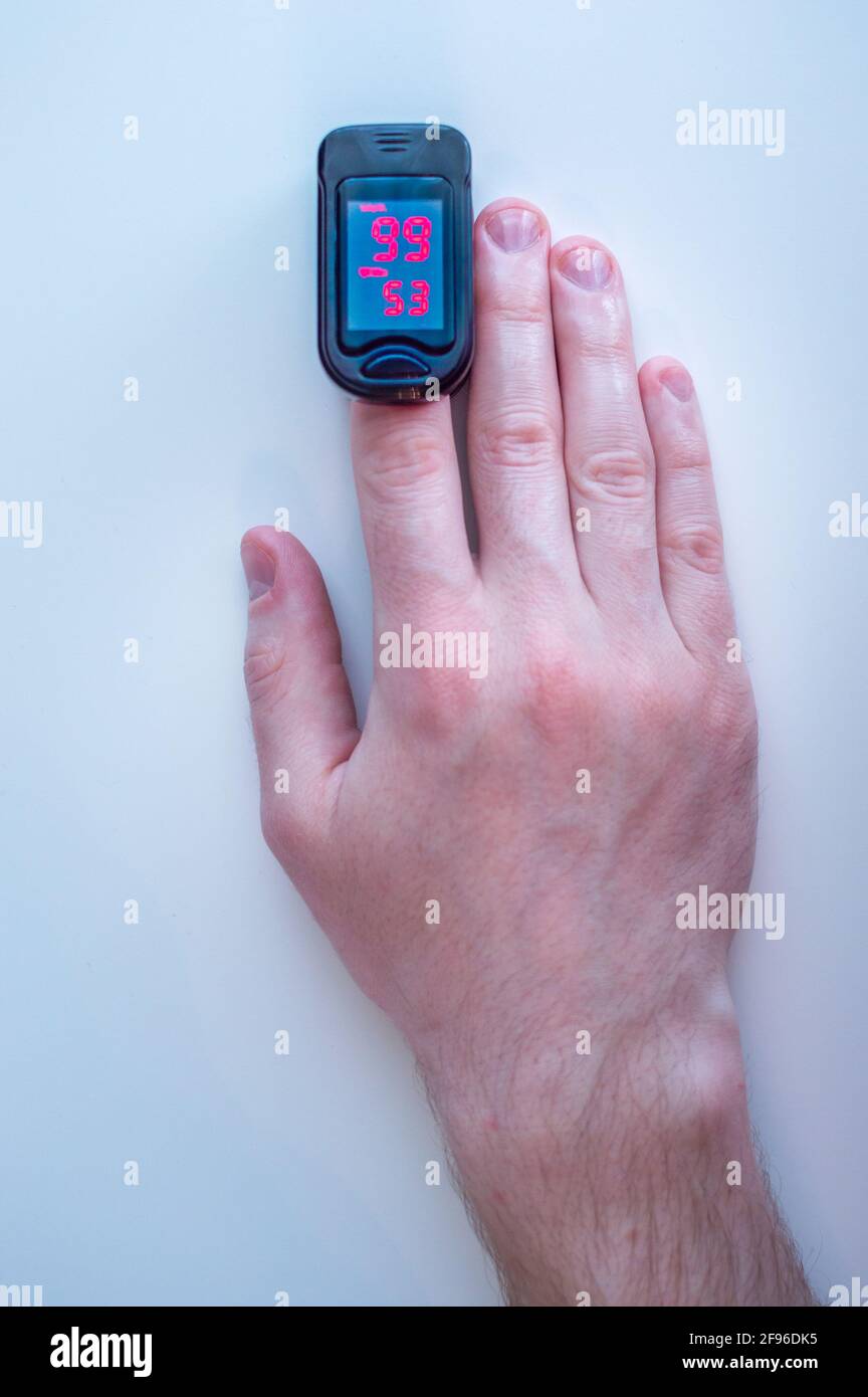 pulse oximeter is placed on the index finger of a man's hand to measure ...