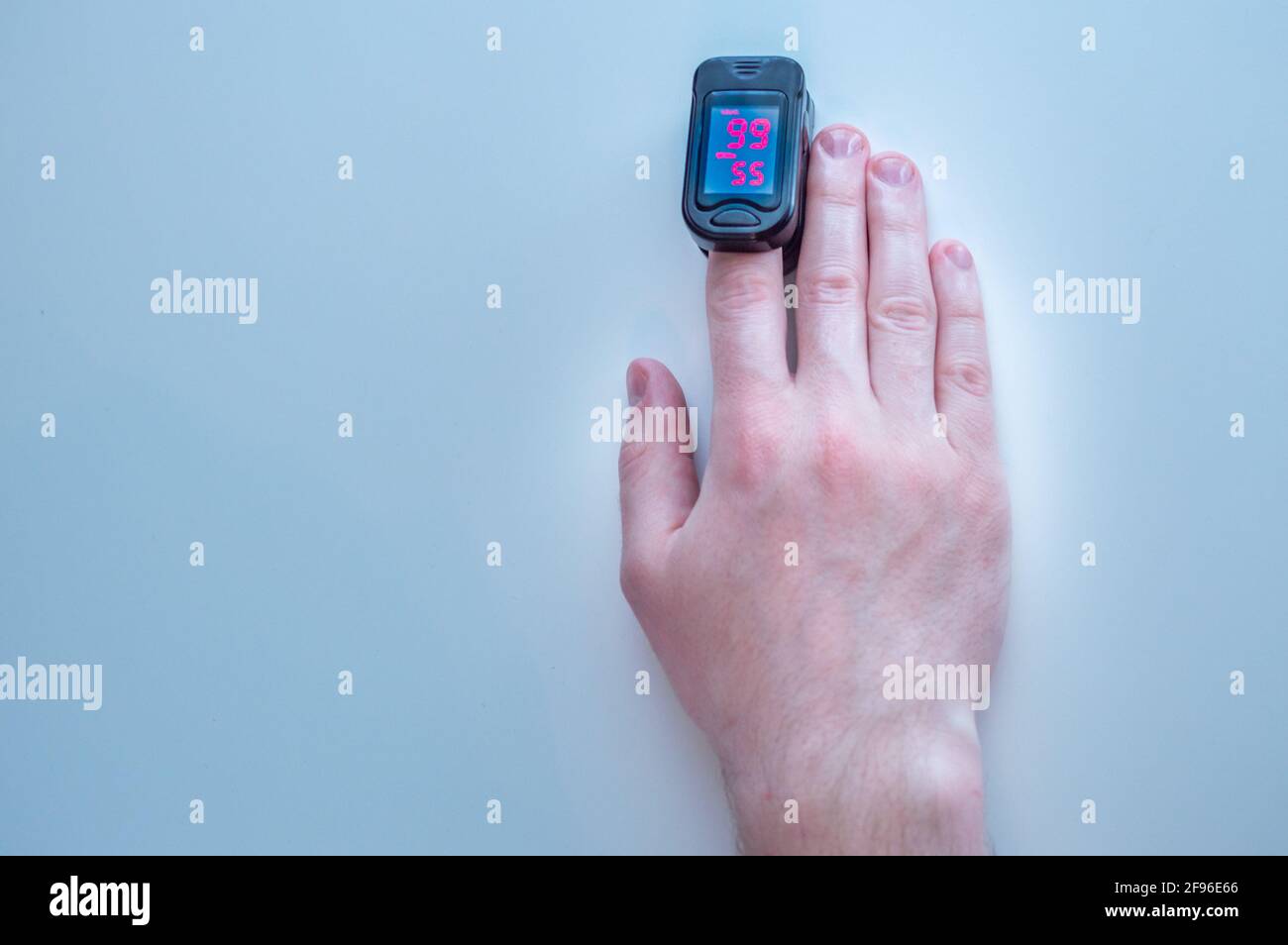 pulse oximeter is placed on the index finger of a man's hand to measure ...