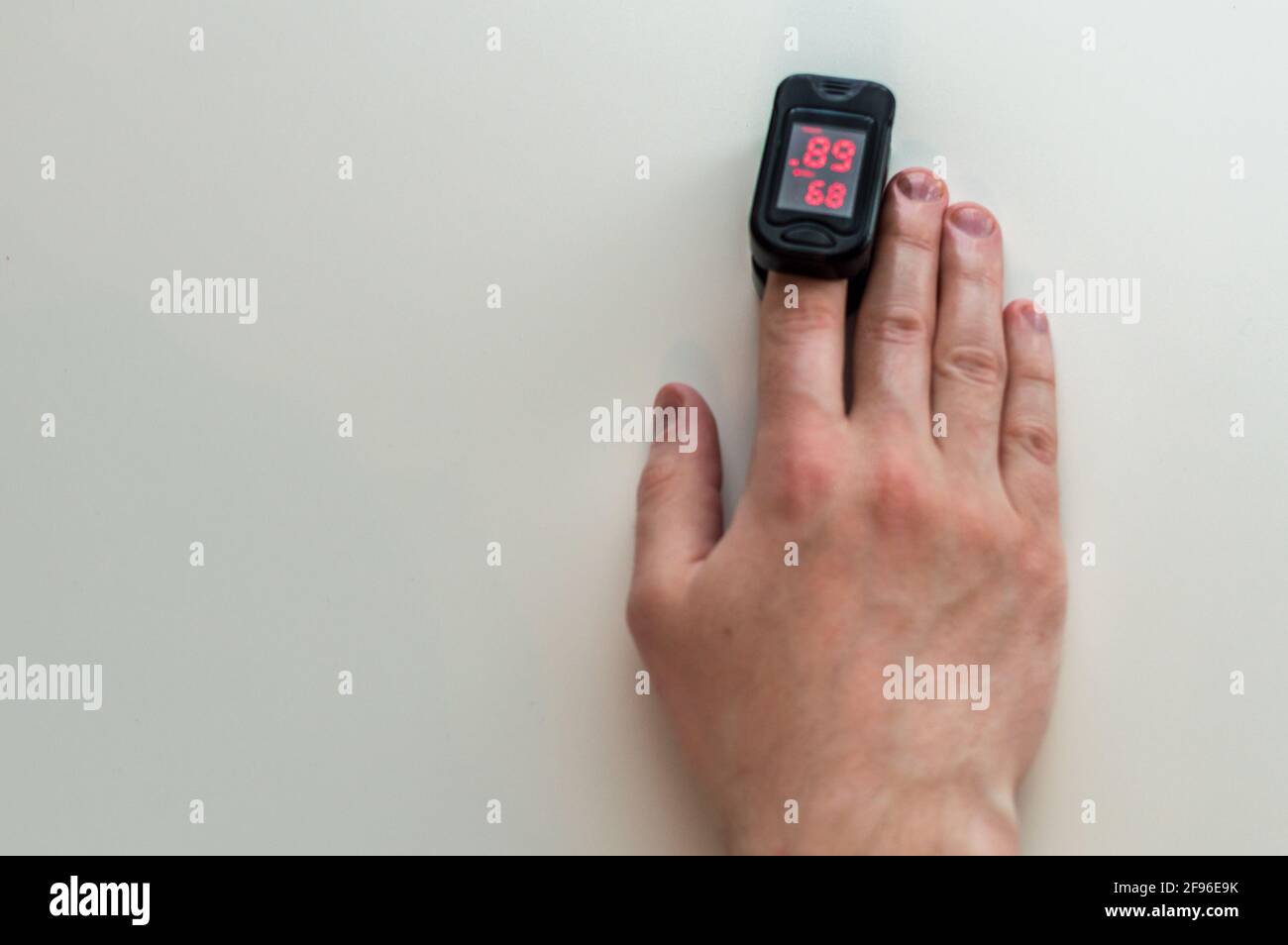 pulse oximeter is placed on the index finger of a man's hand to measure ...