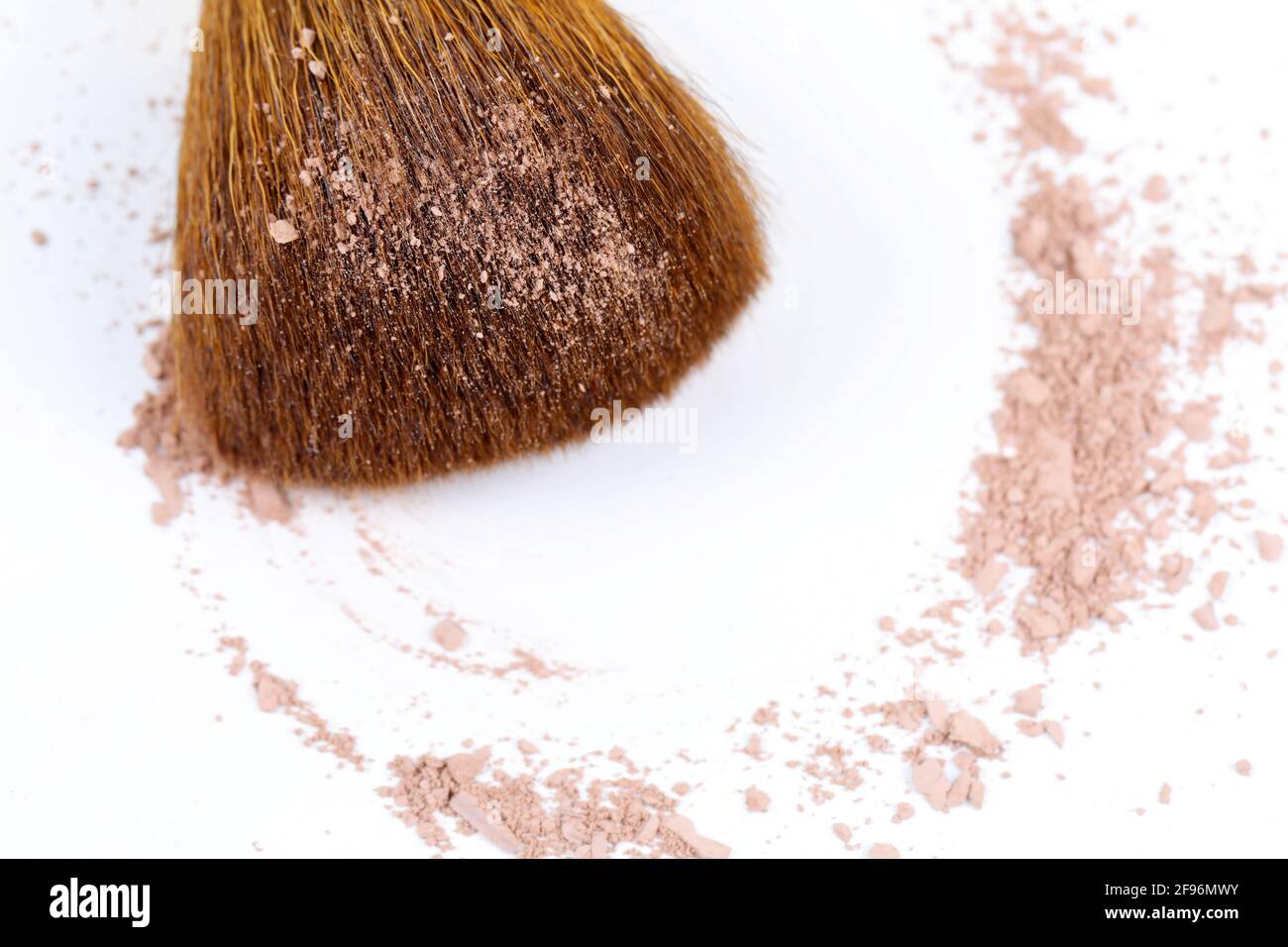 Scattered tan colored facial loose powder and make-up brush isolated on ...