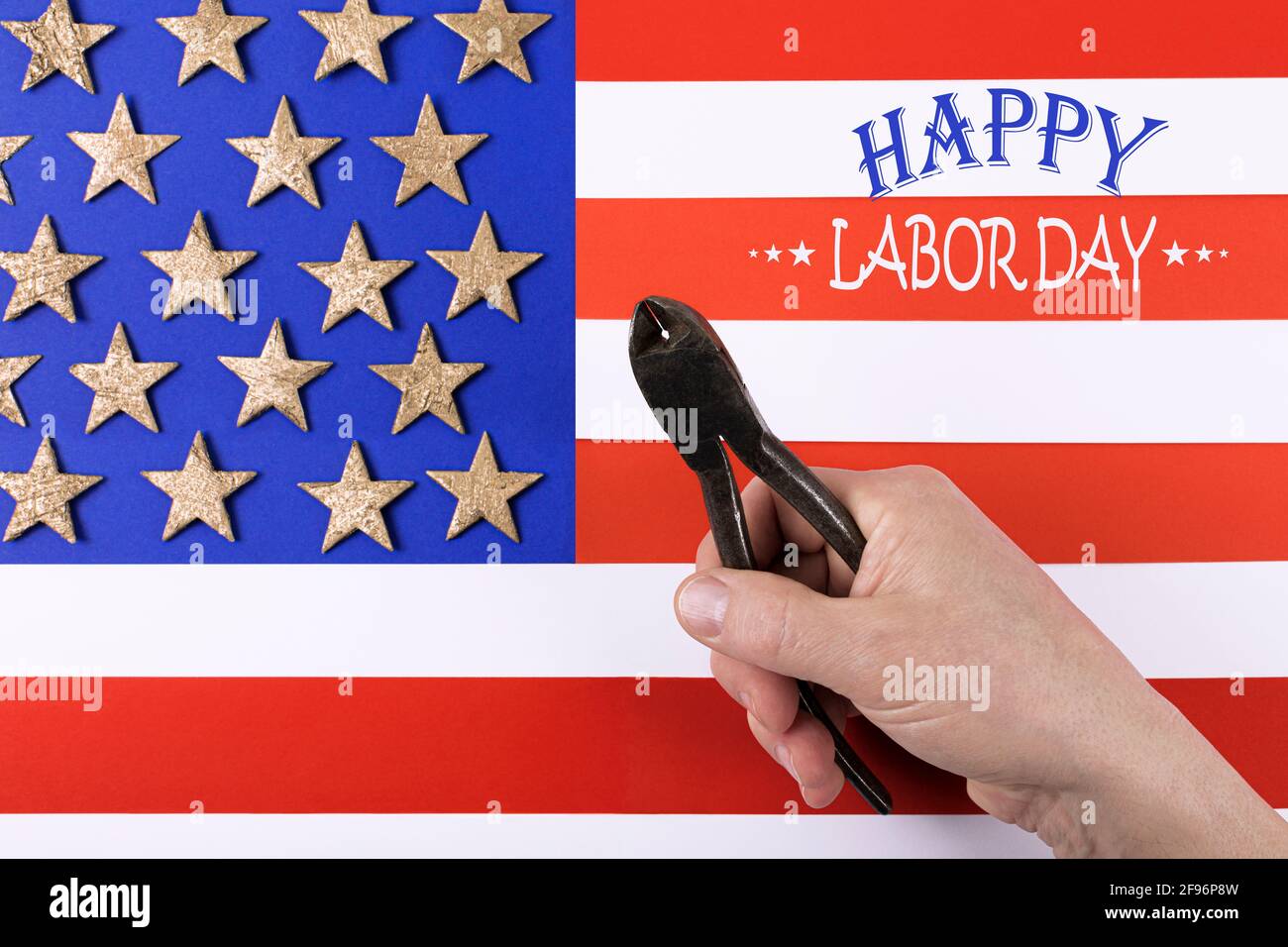 Old metal pliers in man's hand above American flag. Inscription Happy ...