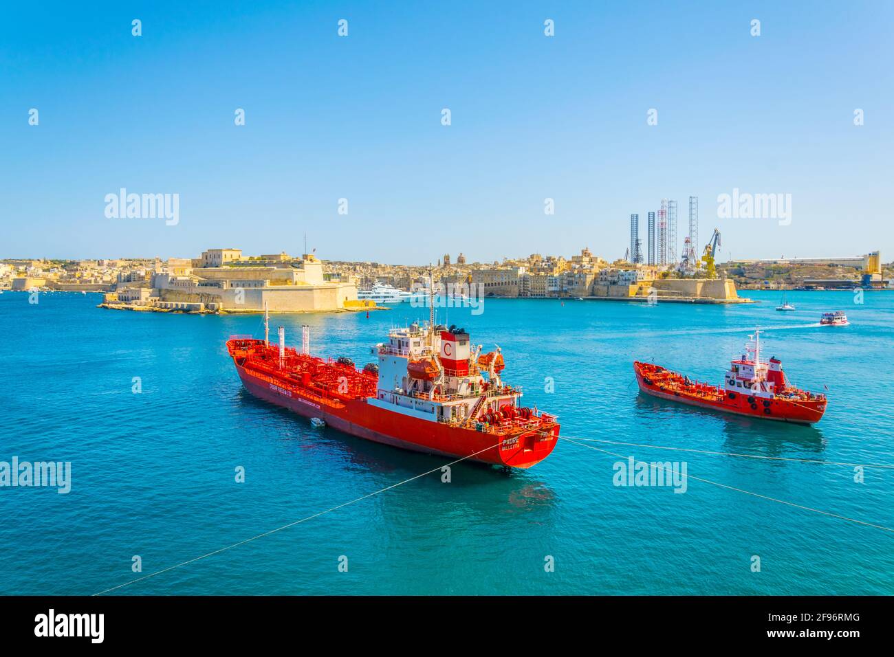 Two cargo ships are facing Birgu town with Fort st. Angelo and Senglea ...