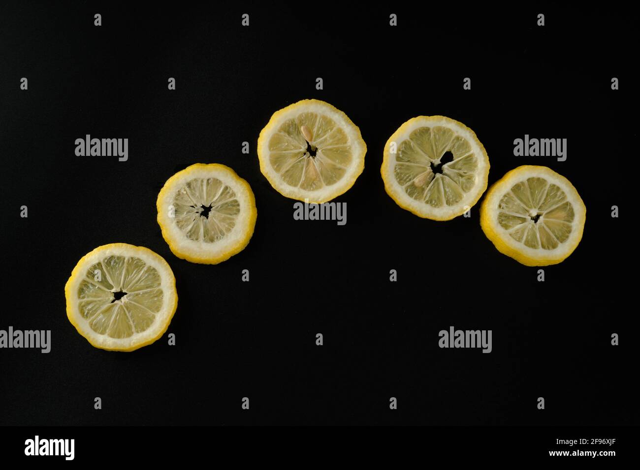 Five lemon slices lined up in a semicircle on a black background Stock ...