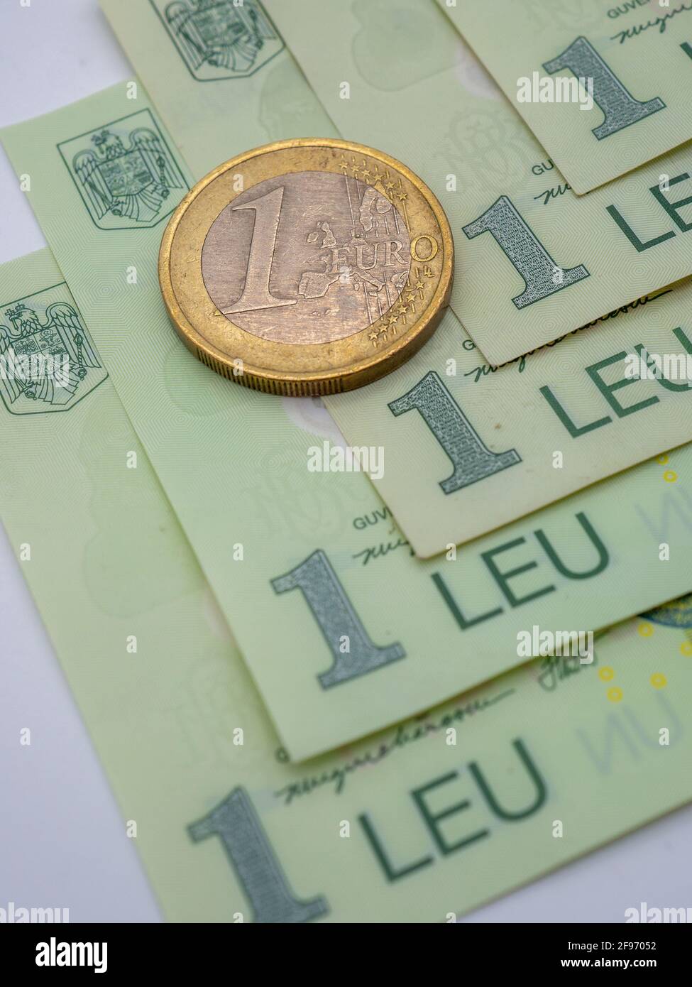 One euro coin put on Romanian banknotes of one leu on a white ...