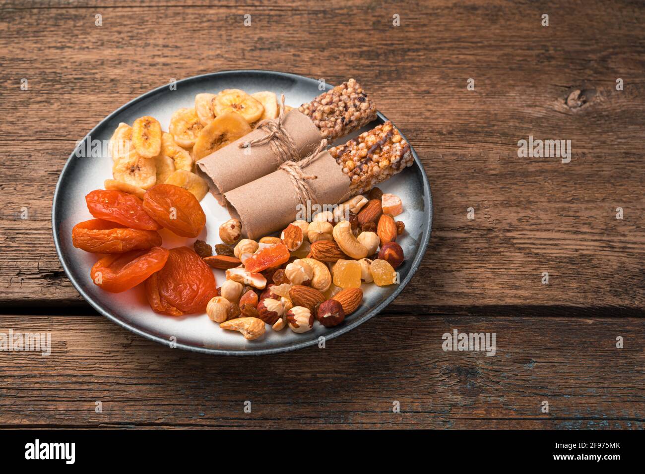 A plate of healthy sweet snacks. Dried apricots, banana chips, nuts and ...