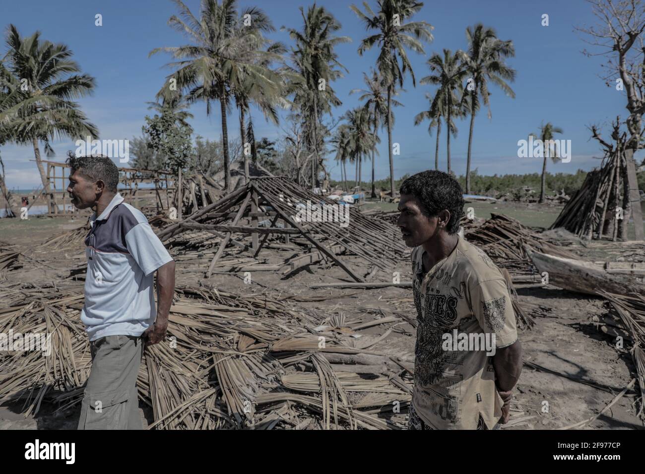 Yulius Fahik (R) and his brother walk around destroyed houses during ...