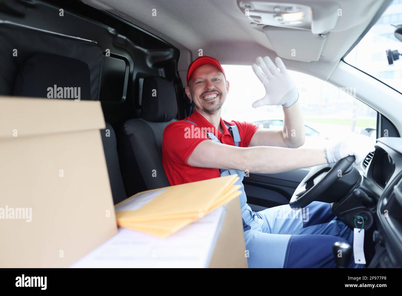 Male driver courier in cab of car waving his hand in greeting Stock ...