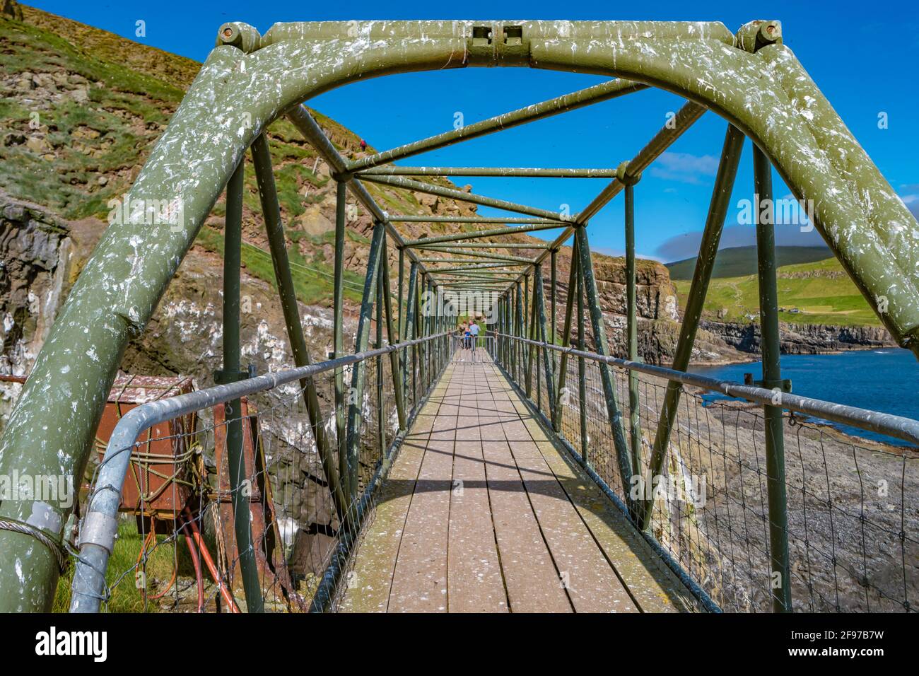 Footbridge over canyon at Mykines island with puffins at Faroe islands ...