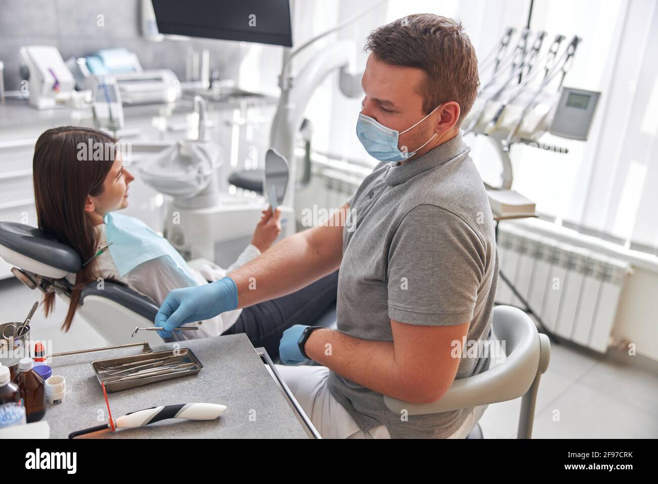 Cheerful positive dentist and client in dentistry. Female client sit in ...