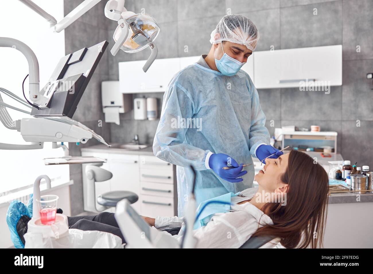 Cheerful positive dentist and client in dentistry. They look at each ...