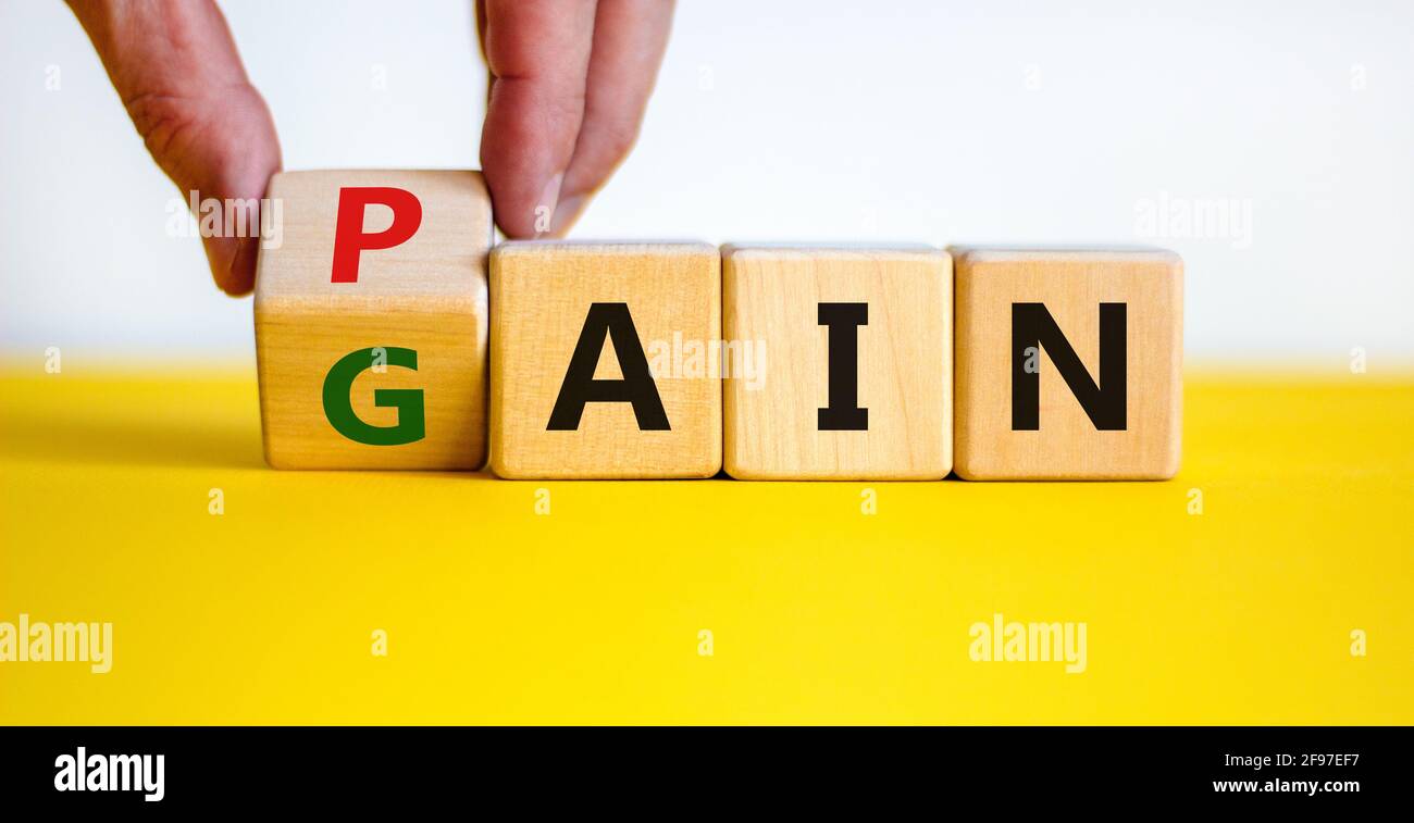 Pain or gain symbol. Businessman turns the wooden cube and changes the ...