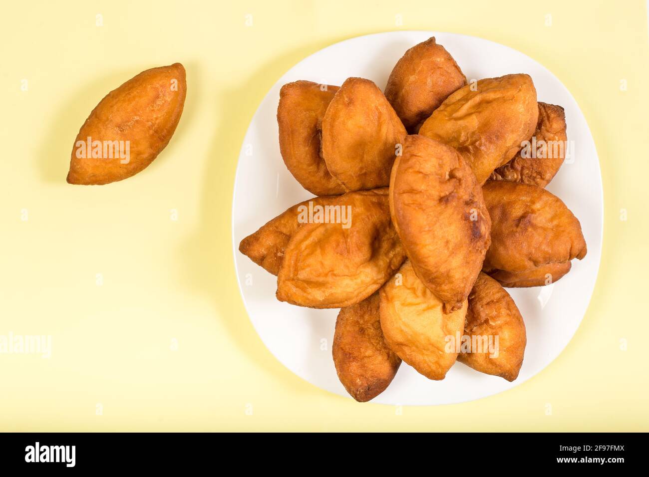 Fried stuffed buns in yellow plate on a natural yellow background with ...