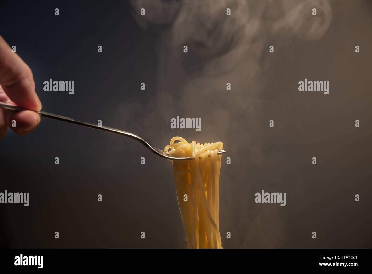 Traditional Italian hot spaghetti hanging from the fork hold by hand ...
