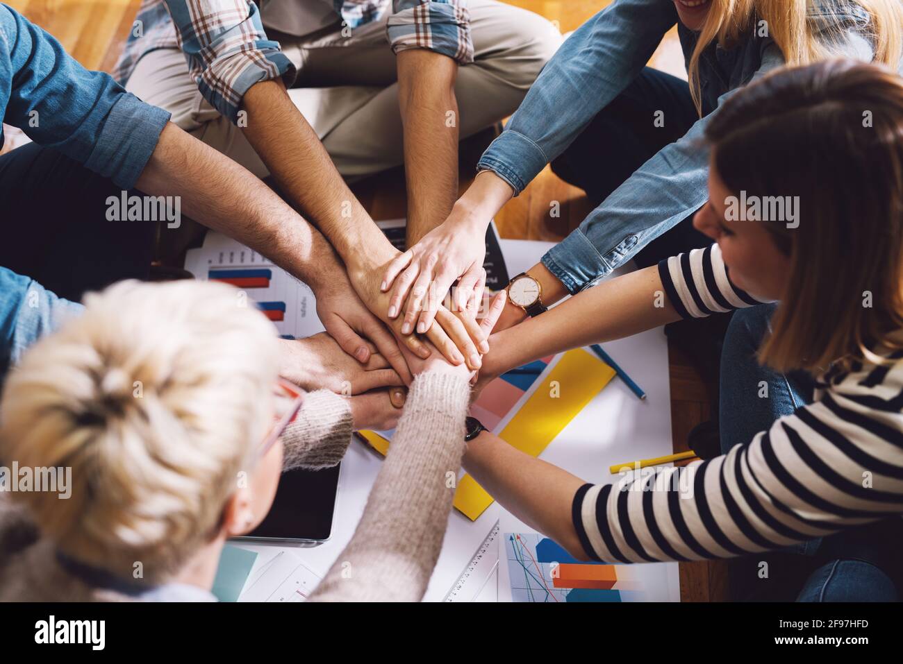 Young joyful coworker people sitting on the floor of the office in the ...