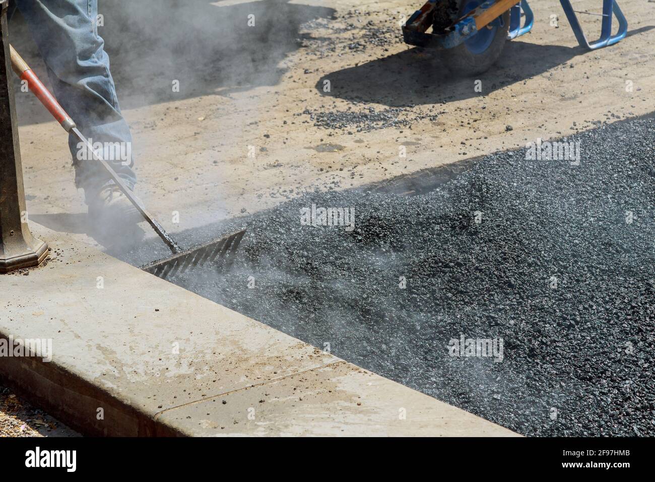 Worker repair asphalt covering while laying asphalt new road surface a ...