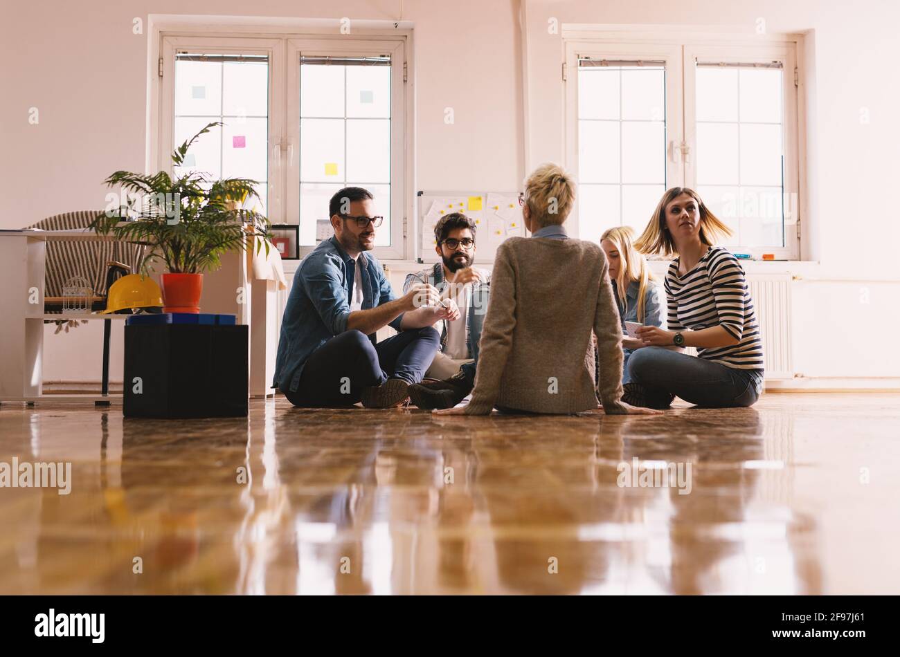 Modern cheerful young people working together on the office floor and ...
