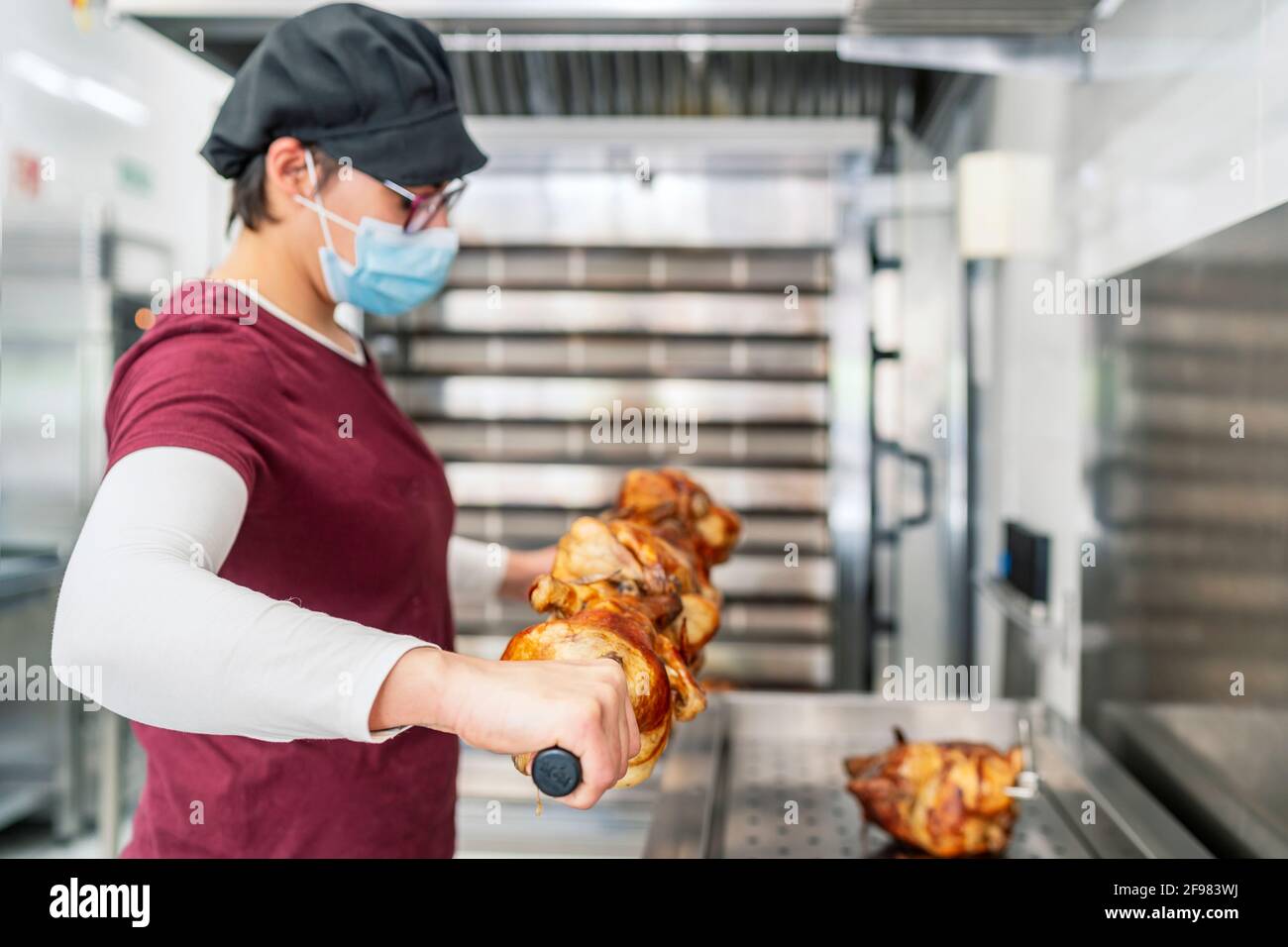 female cook taking chickens out of the oven Stock Photo - Alamy
