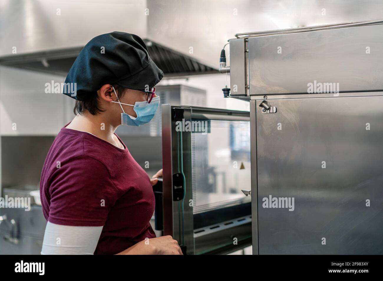 female cook looking at the food that is in the oven Stock Photo - Alamy