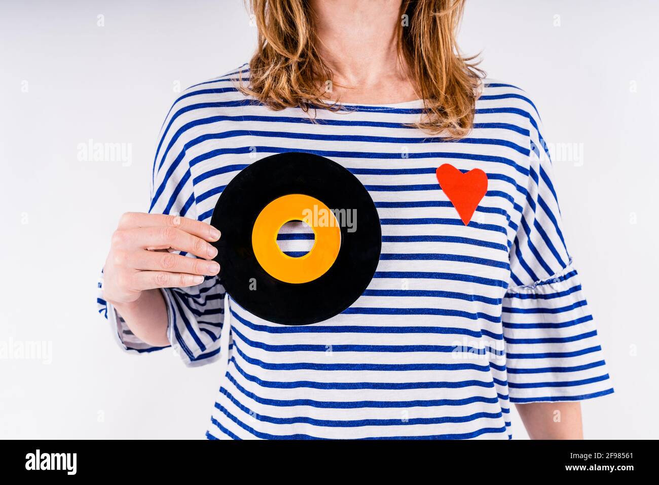 Girl dressed in blue and white striped dress holding a vinyl record o ...