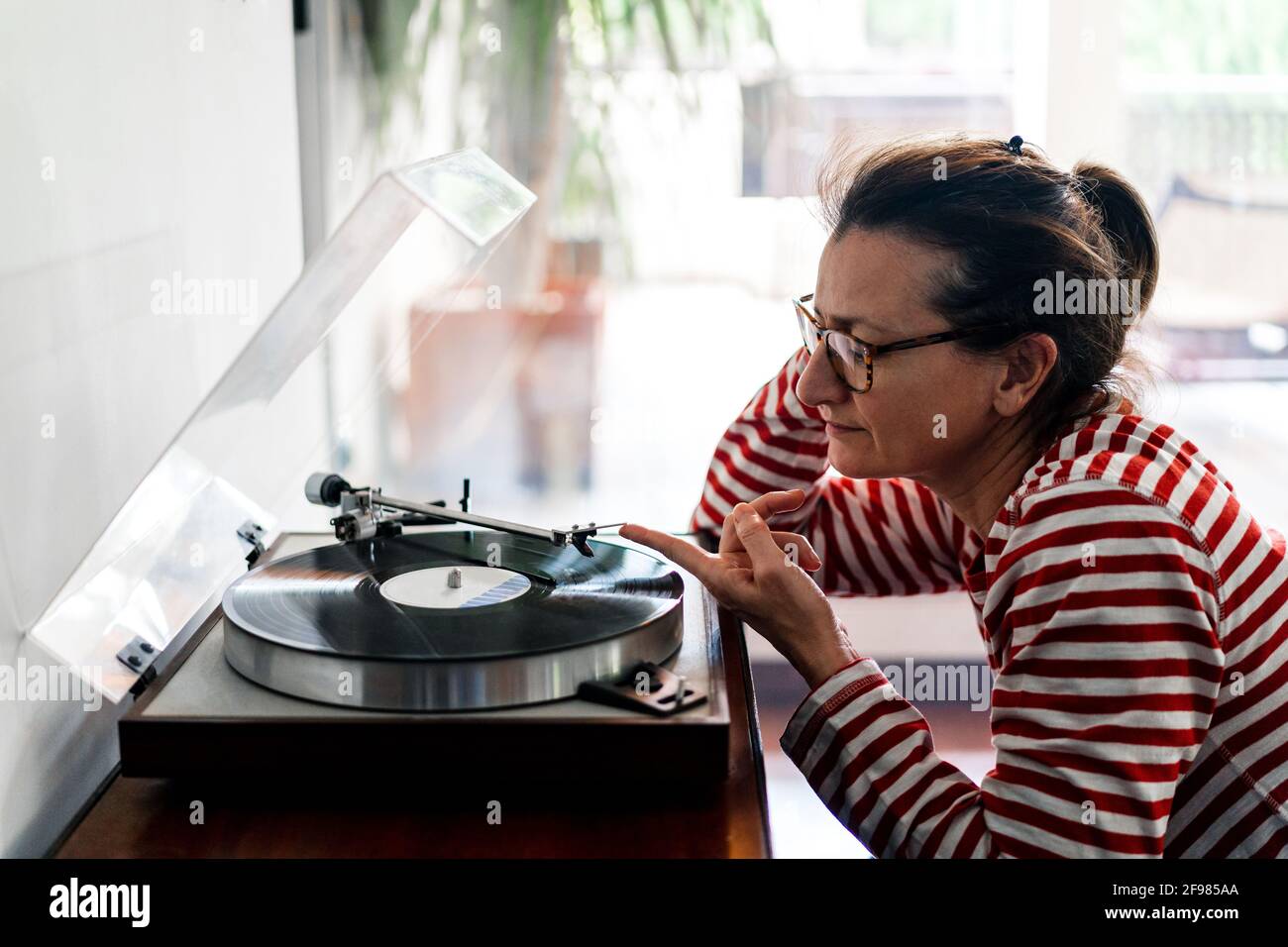 woman putting a vinyl record on a record player inside a house Stock ...