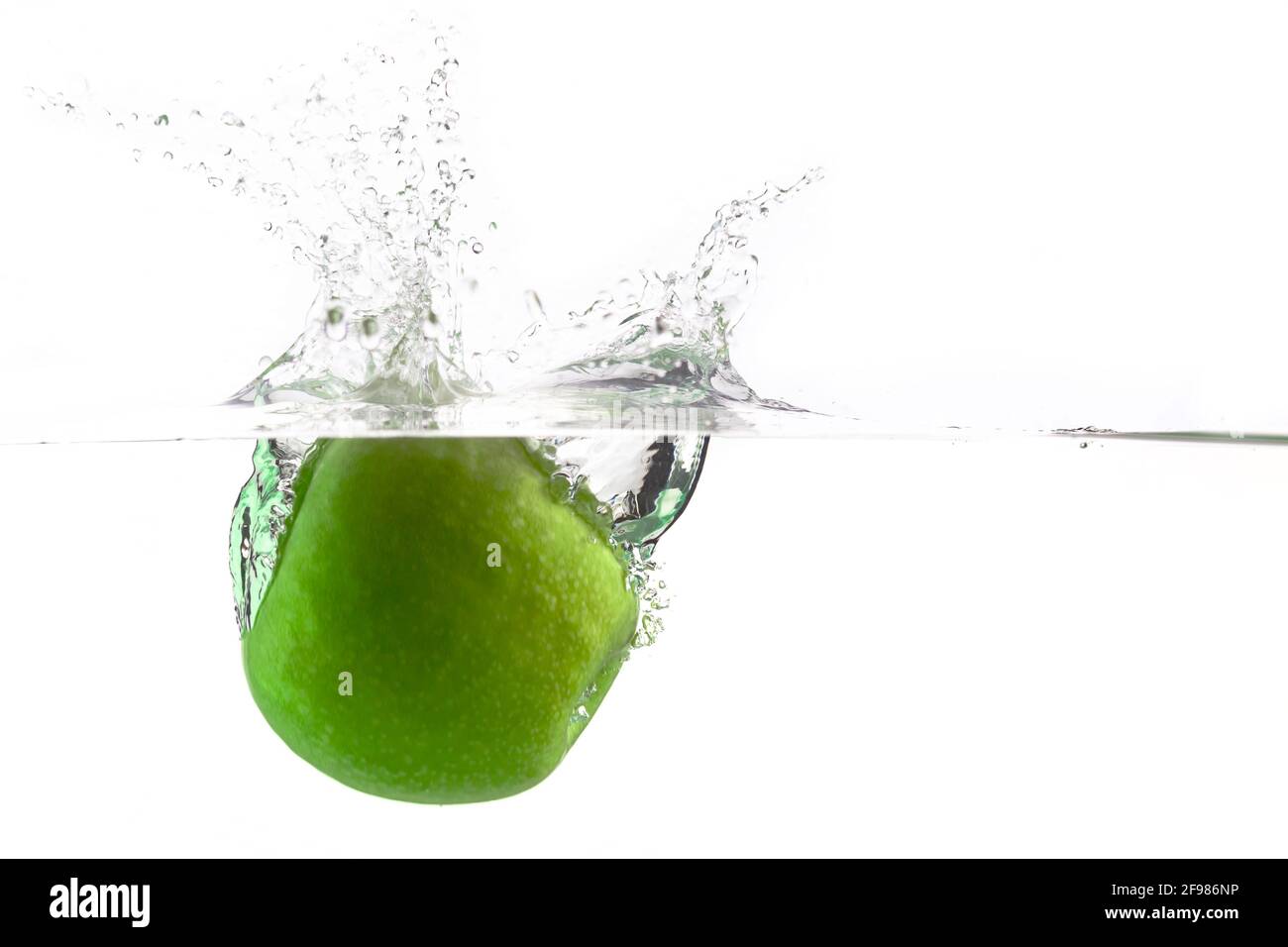 drop one green apple into the water with splashes on a white background ...