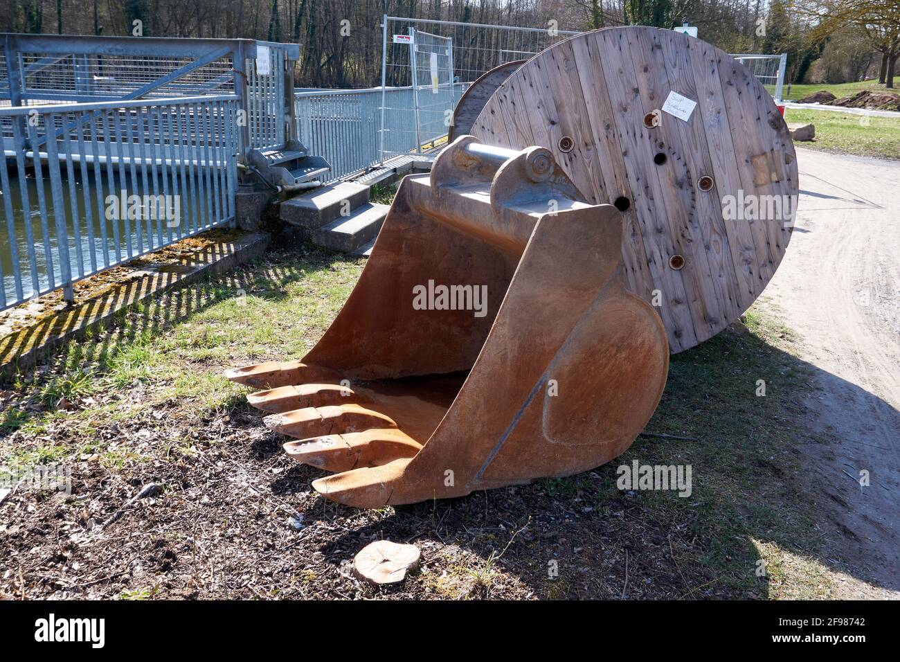 Antique excavator bucket isolated on the ground near the metallic fence ...