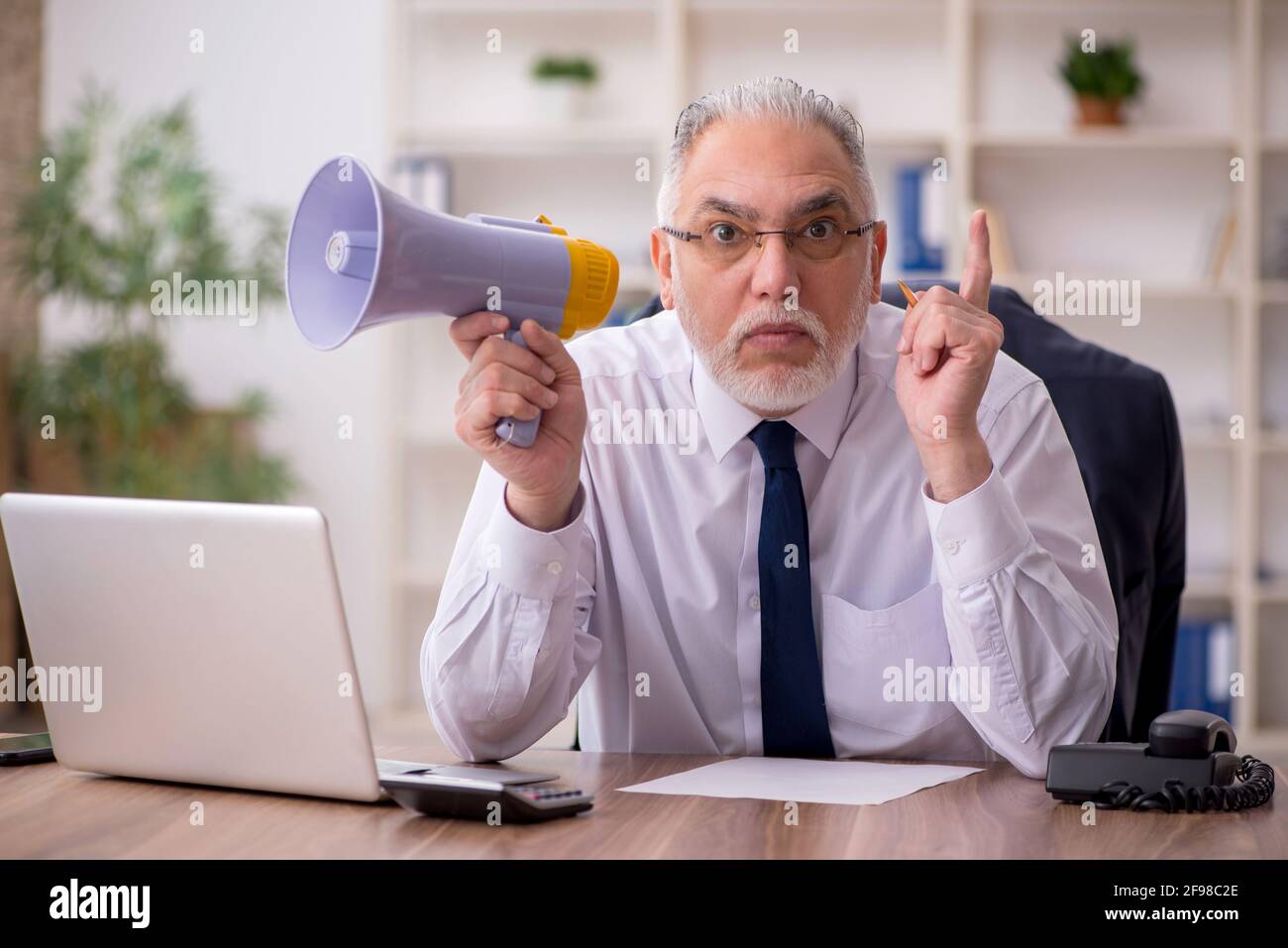 Old businessman employee holding megaphone at workplace Stock Photo - Alamy