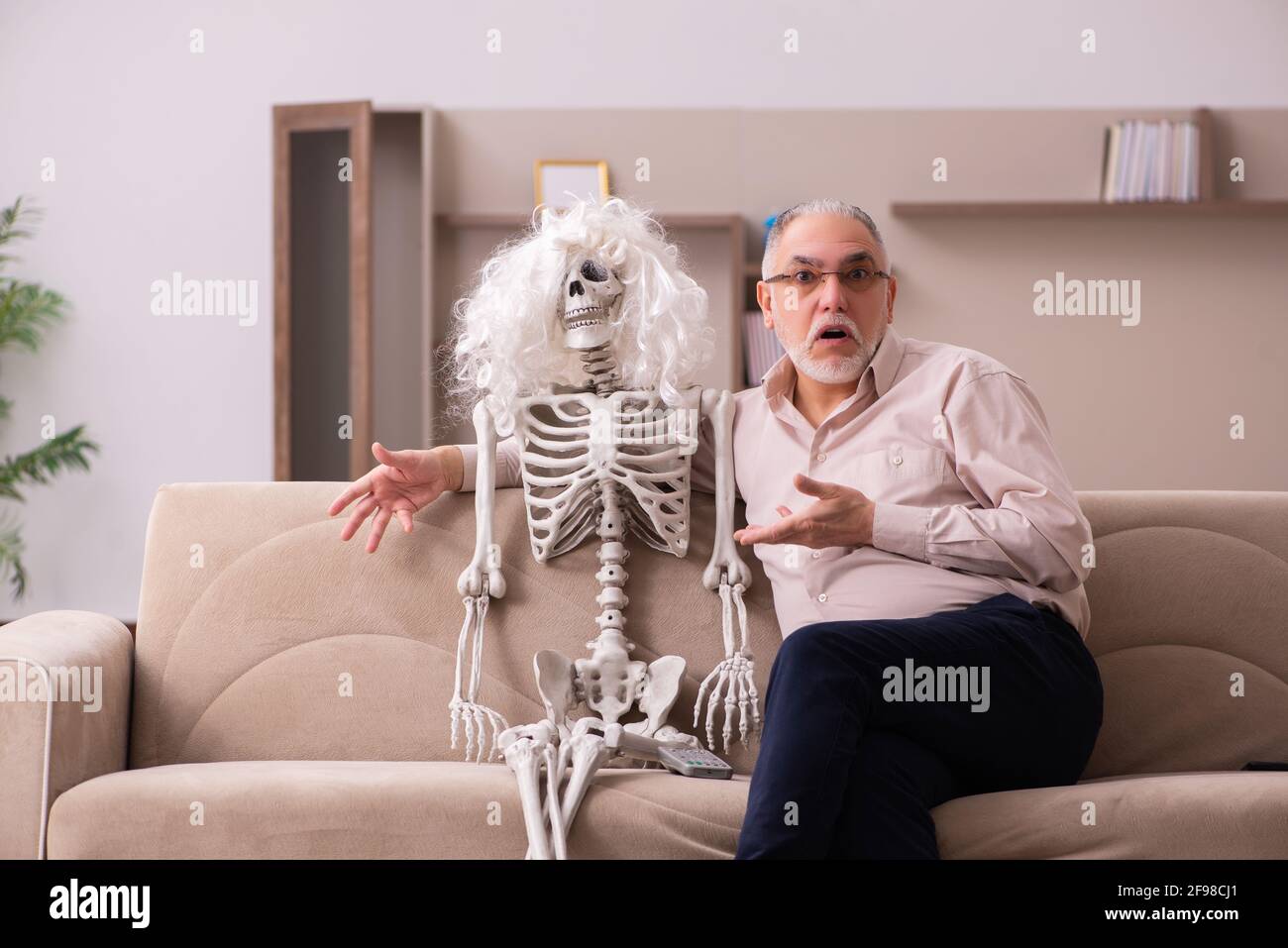 Old man sitting on the sofa with the female skeleton in undying love ...