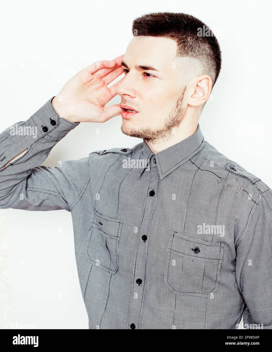 Portrait of a smart serious young man standing against white background ...