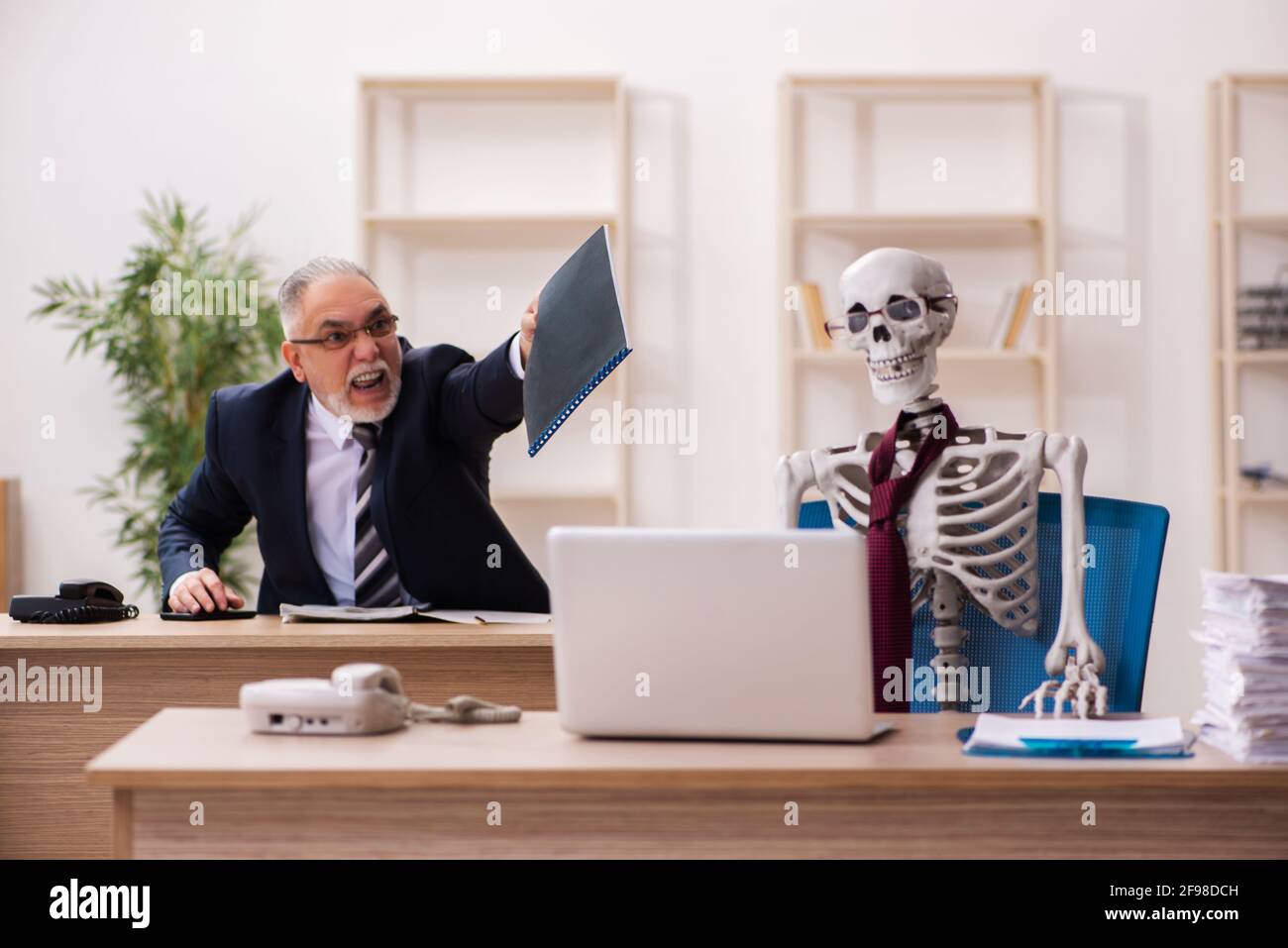 Dead employee working in the office in funny concept Stock Photo - Alamy
