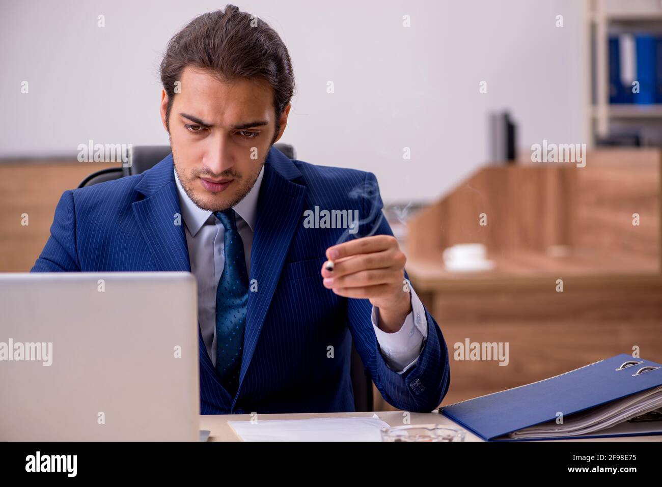 Young man employee smoking cigarettes in the office Stock Photo - Alamy