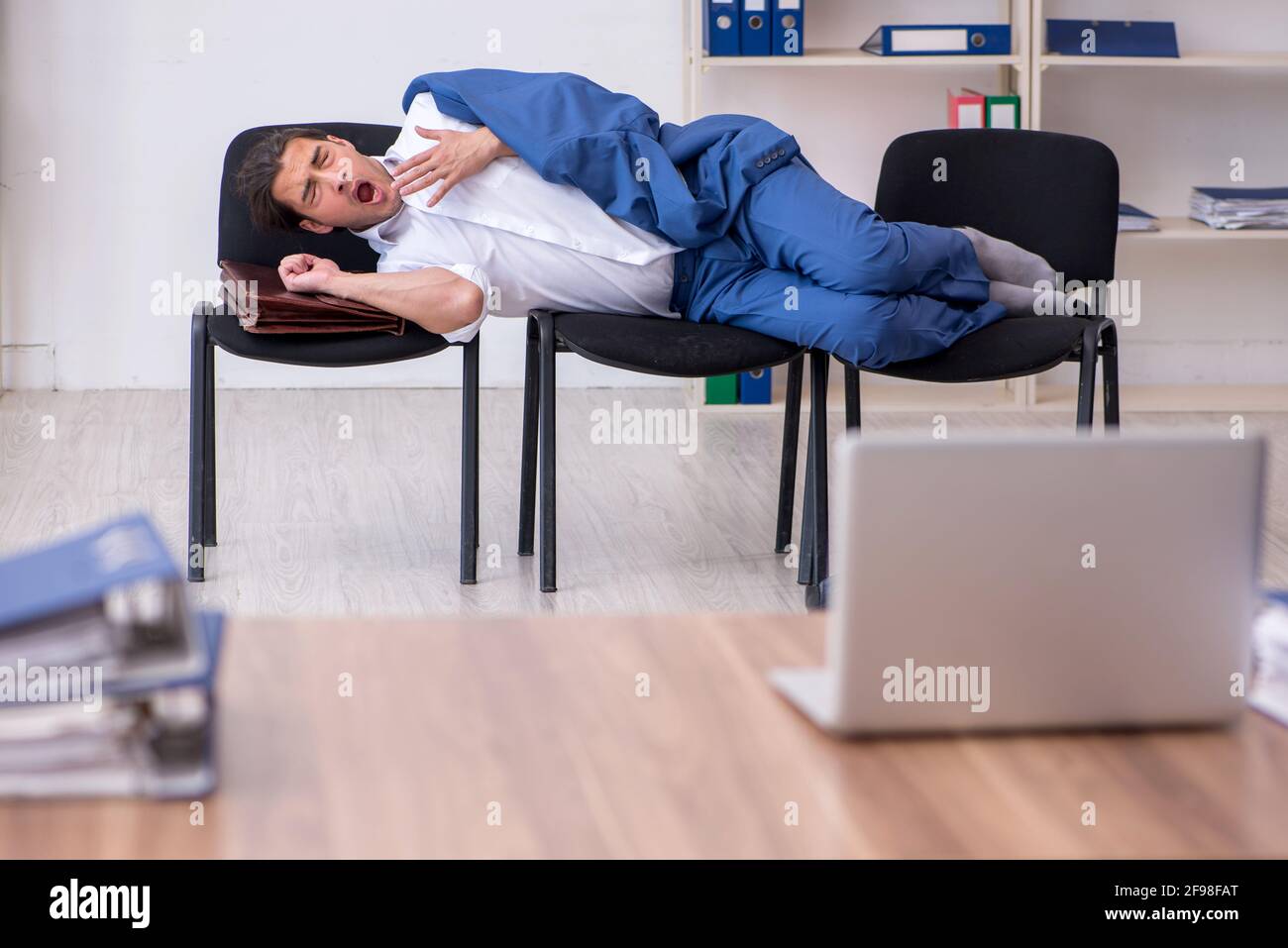 Young employee sleeping in the office on chairs Stock Photo - Alamy
