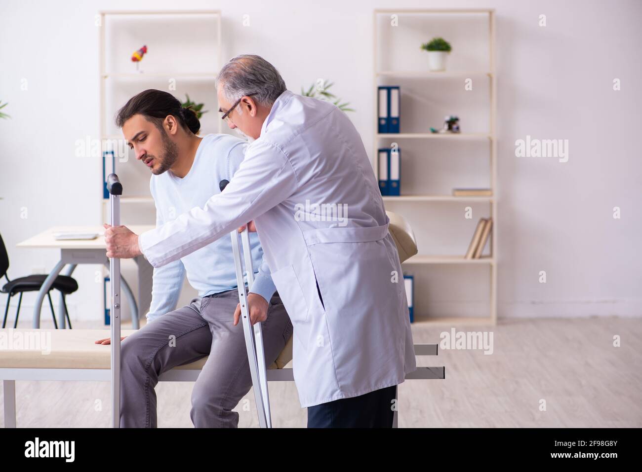 Leg injured man visiting old doctor osteopath Stock Photo - Alamy