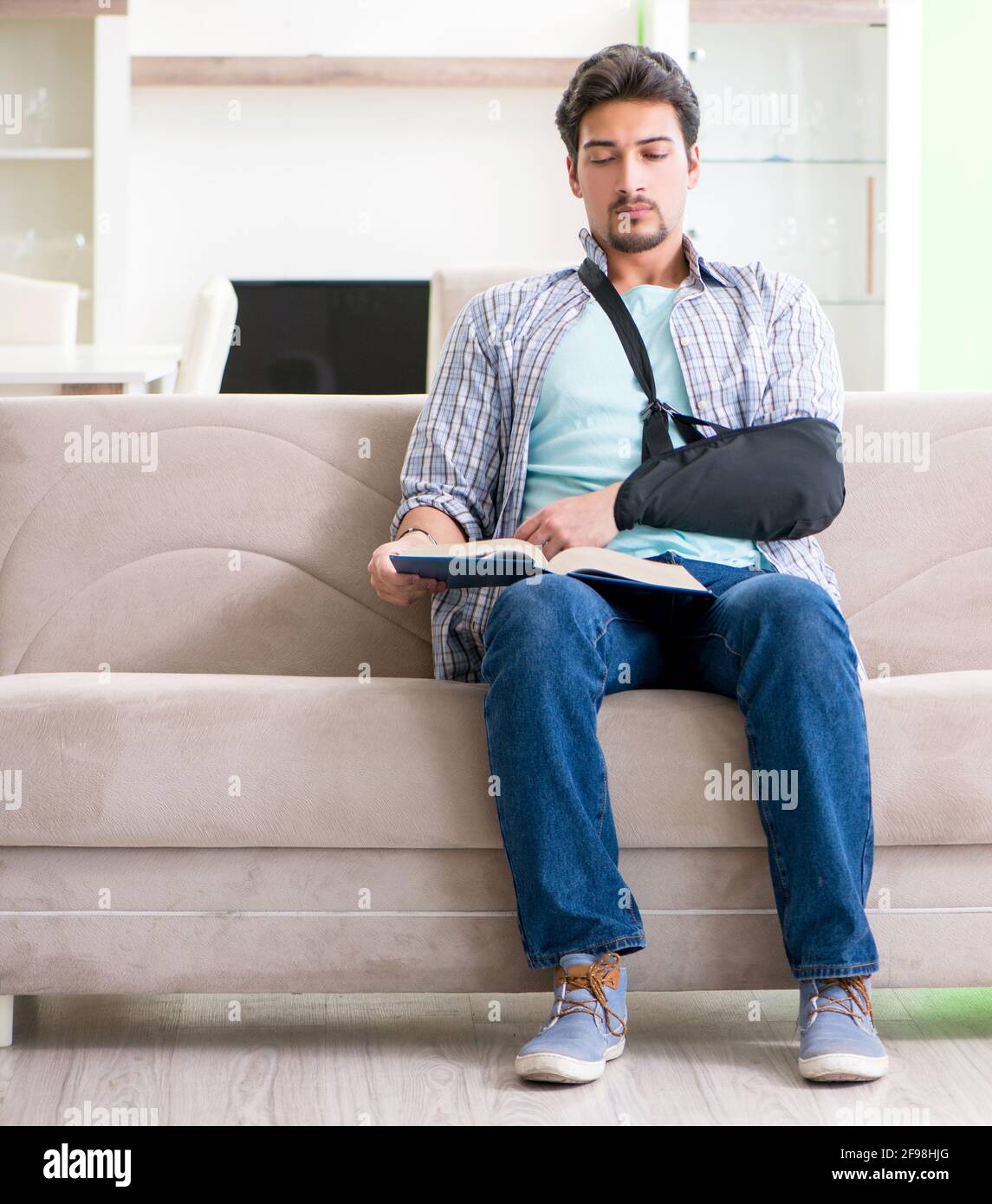 The young student man with hand injury sitting on the sofa Stock Photo ...