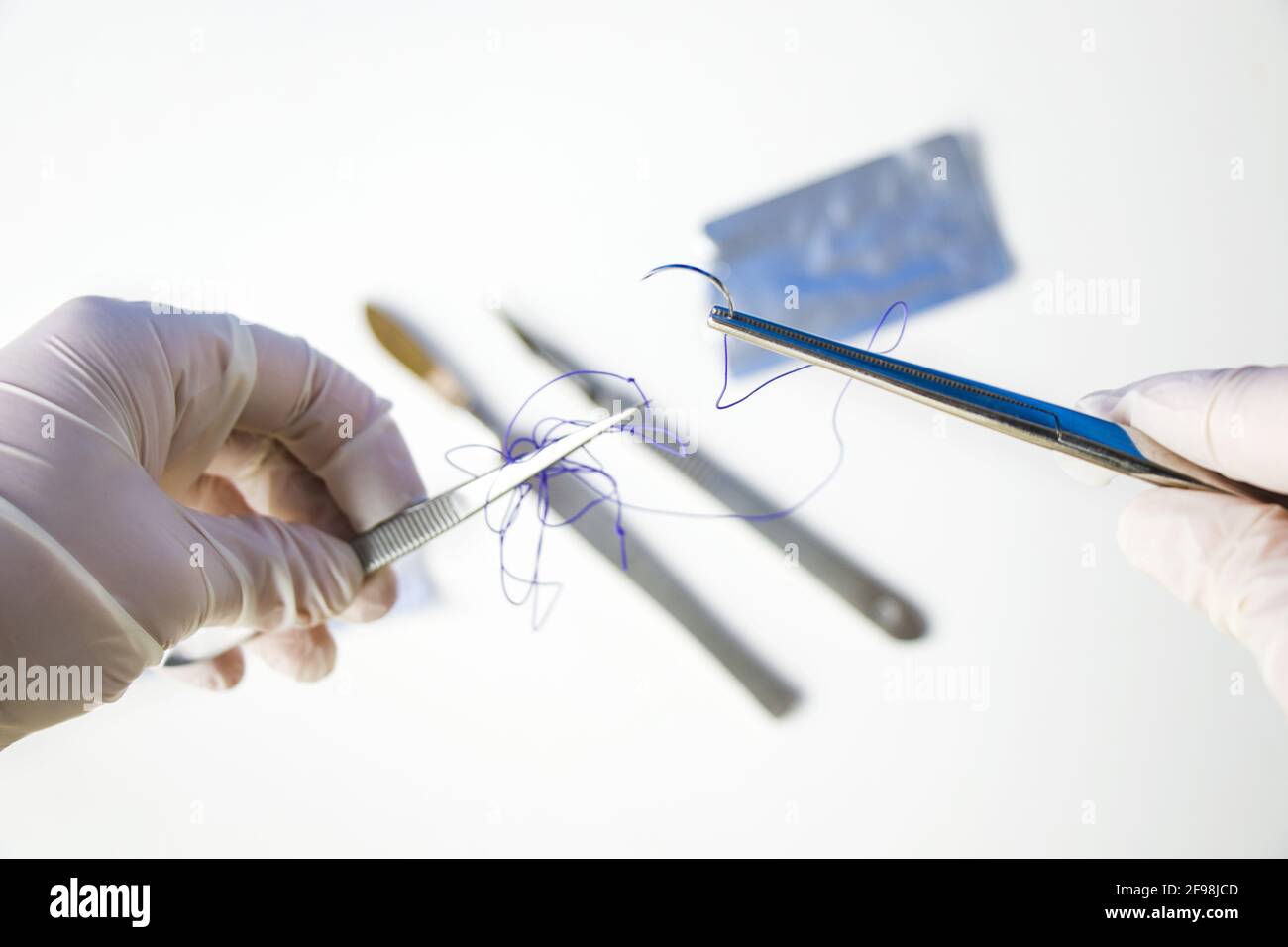 Closeup shot of a doctor holding a surgical needle and thread on a ...