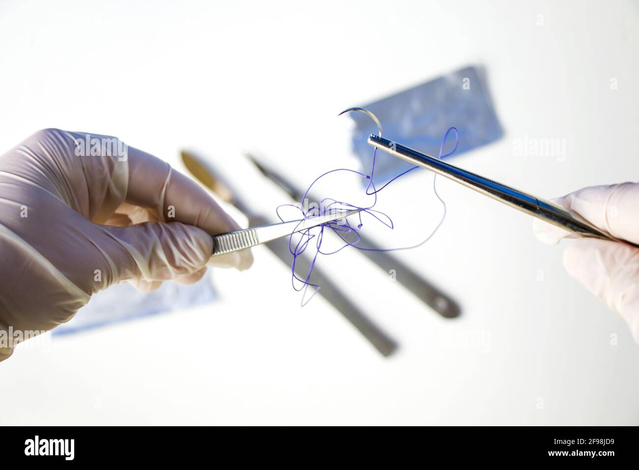 Closeup shot of a doctor holding a surgical needle and thread on a ...