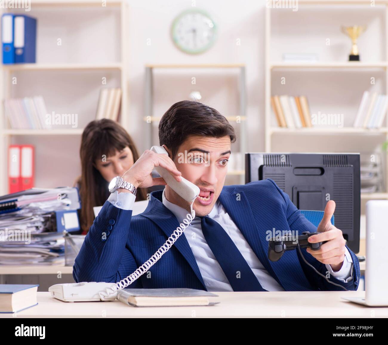 The man playing games in office while colleague is busy Stock Photo - Alamy